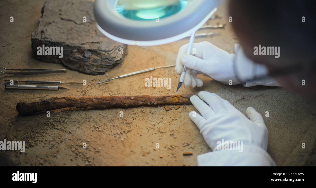 Senior archaeologist cleans fossil ancient wooden spear under lamp ...