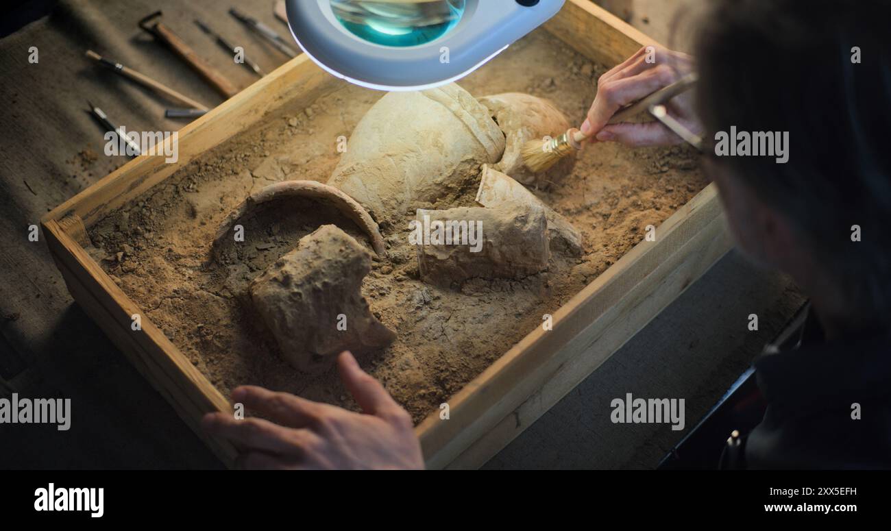Close up of mature archaeologist cleaning cultural heritage of extinct civilization from sand ...
