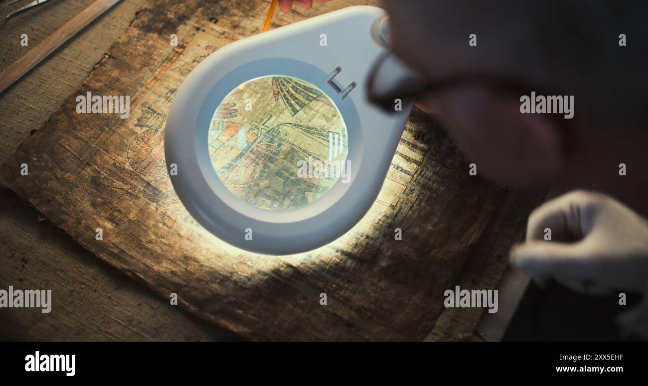 Senior archaeologist looks through magnifying lamp, studies ancient ...