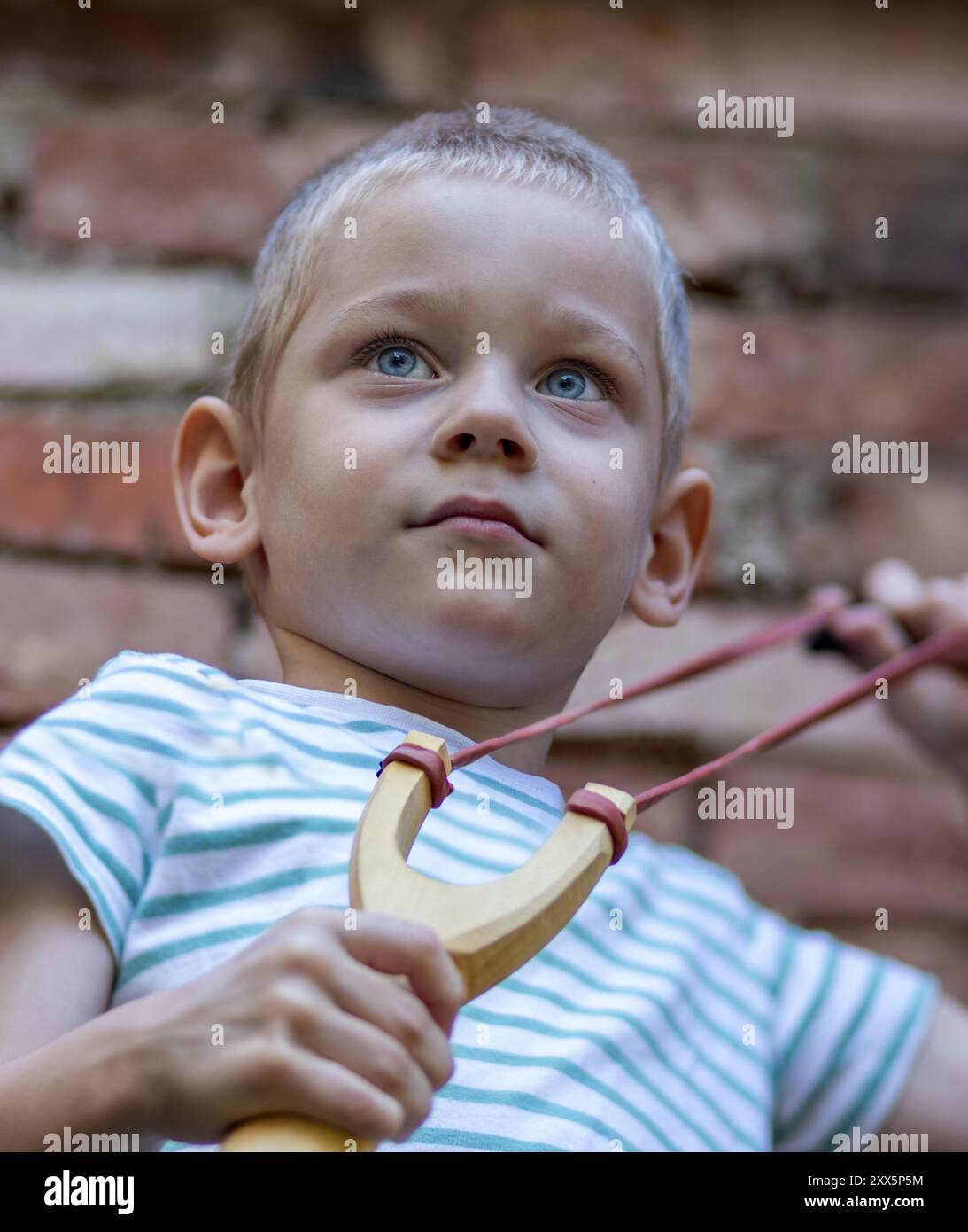 A little boy is playing with a slingshot on the street Stock Photo - Alamy