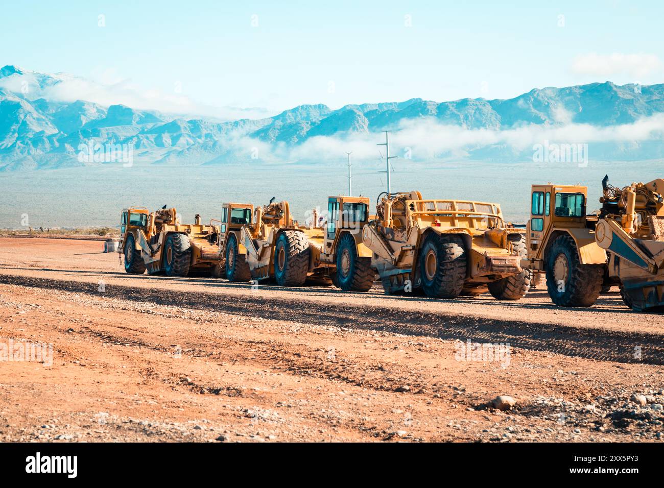 A fleet of earth movers prepares barren desert land for new housing ...