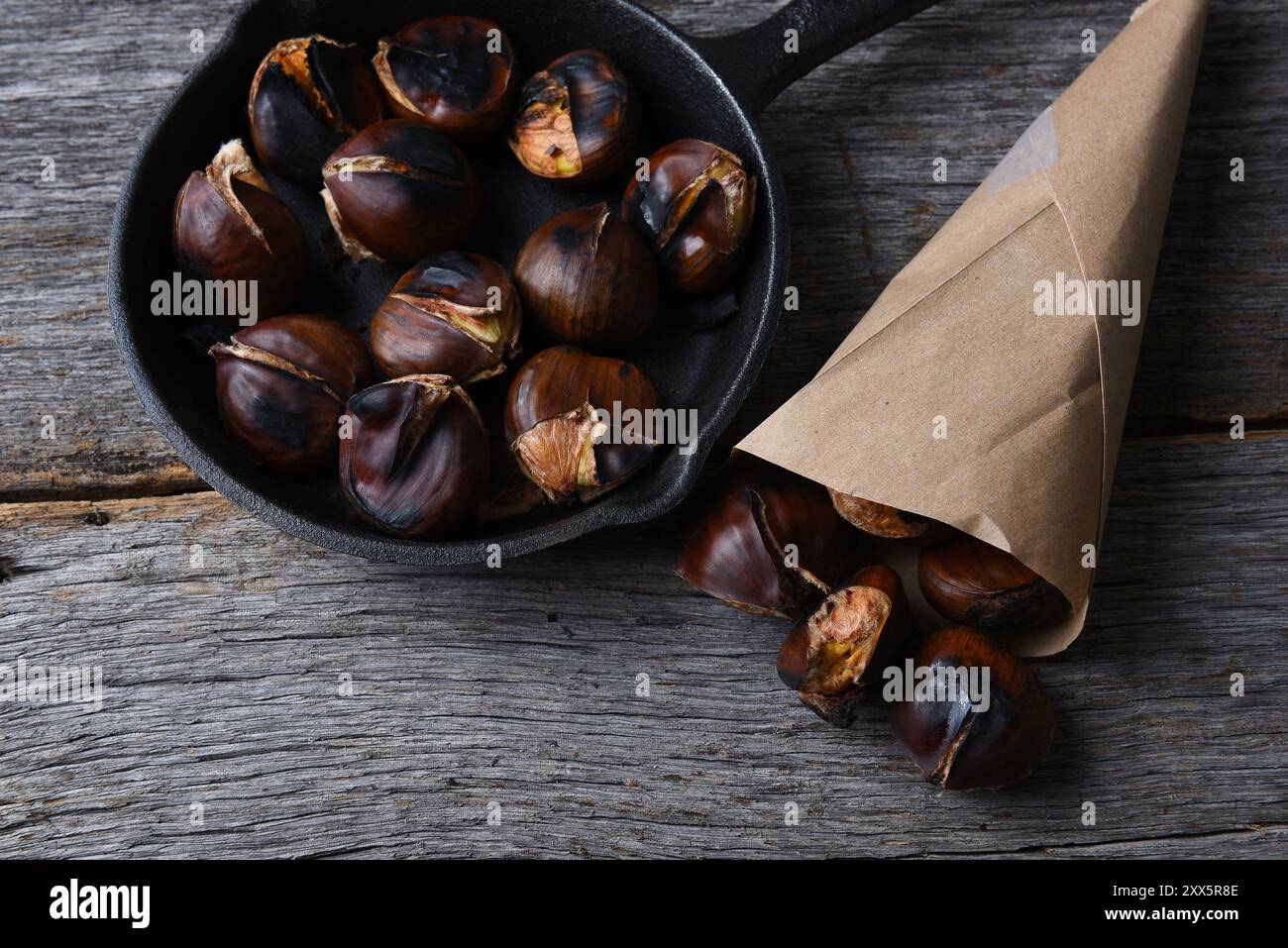 Roasted chestnuts in pan and a paper sack full of cooked nuts Stock ...