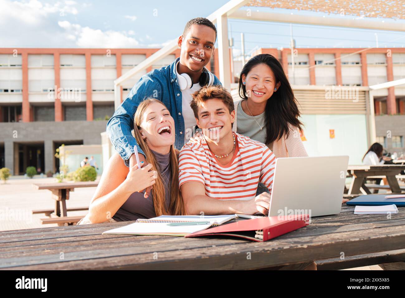 Diverse group of male and female students, smiling and looking at camera while studying together ...