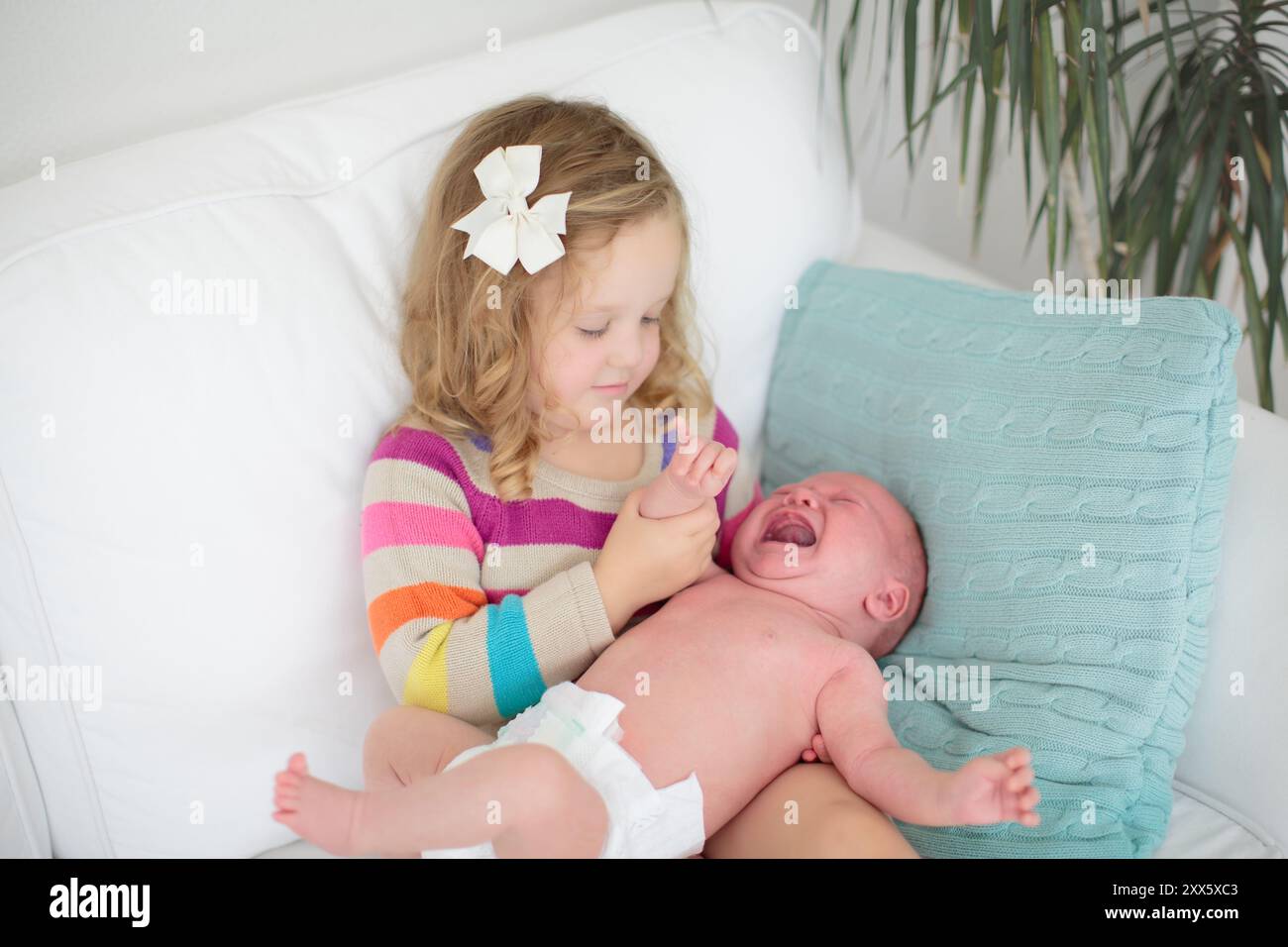Siblings meet newborn baby in hospital. Child holding new infant ...