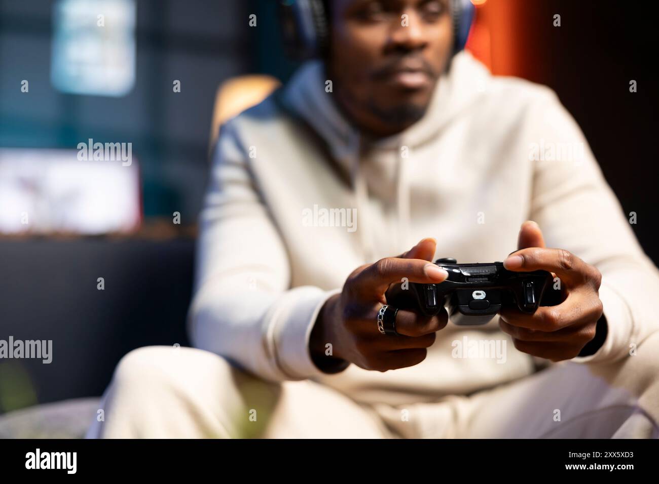 BIPOC man playing shooter videogame in neon lit apartment, holding ...