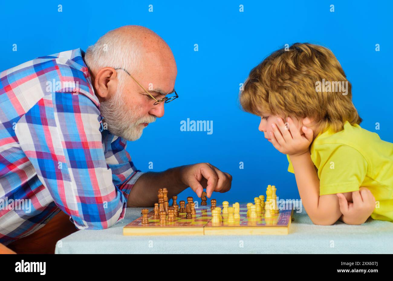 Chess competition. Grandfather and grandson playing chess. Senior man ...