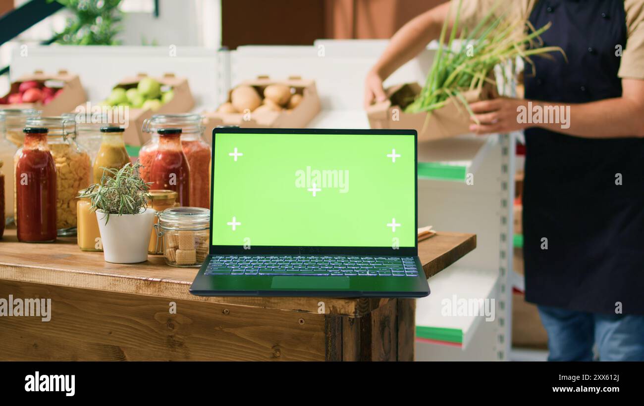 Laptop displaying greenscreen in bio shop filled with freshly harvested ...