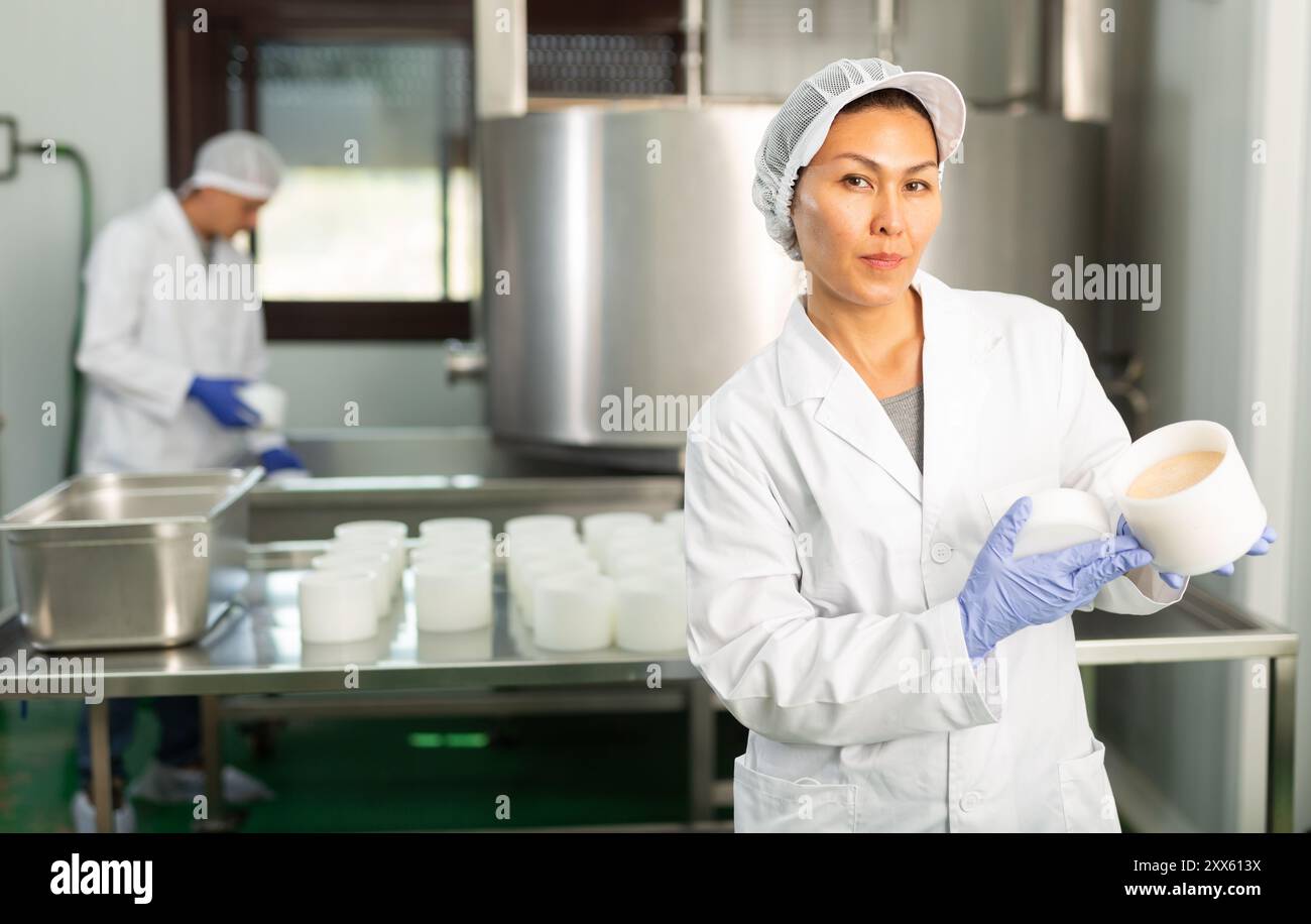 Woman wearing uniform showing cottage cheese production process on ...