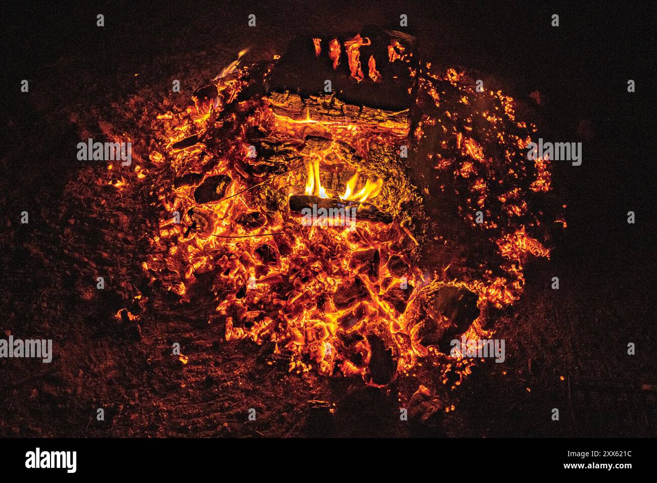 Campfire coals burning with beautiful red, hot texture and logs burning ...