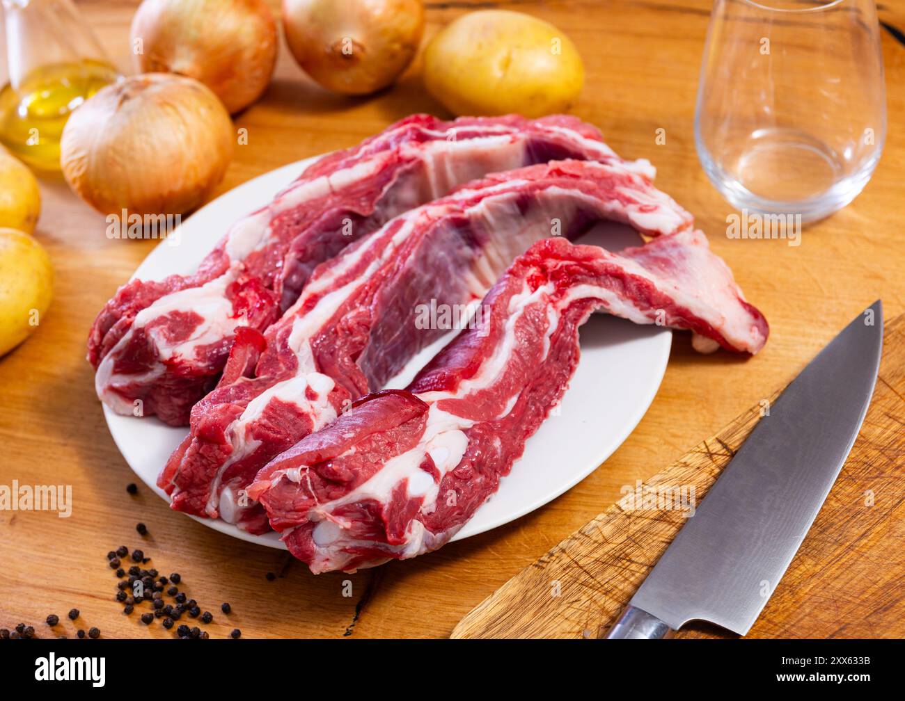 Raw beef ribs on board, potato tubers and whole onions Stock Photo - Alamy