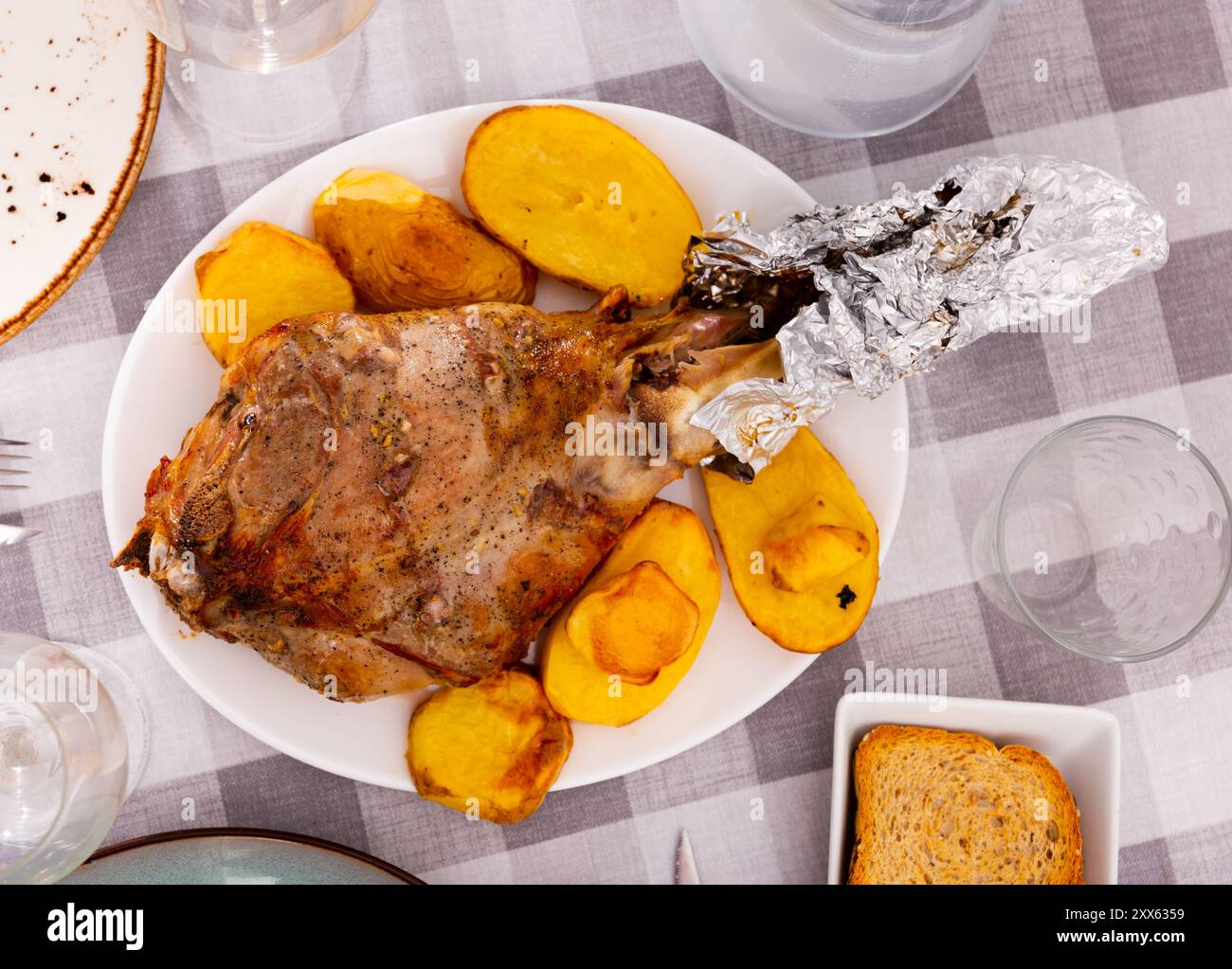 Whole leg of lamb with baked potato on serving table closeup Stock ...