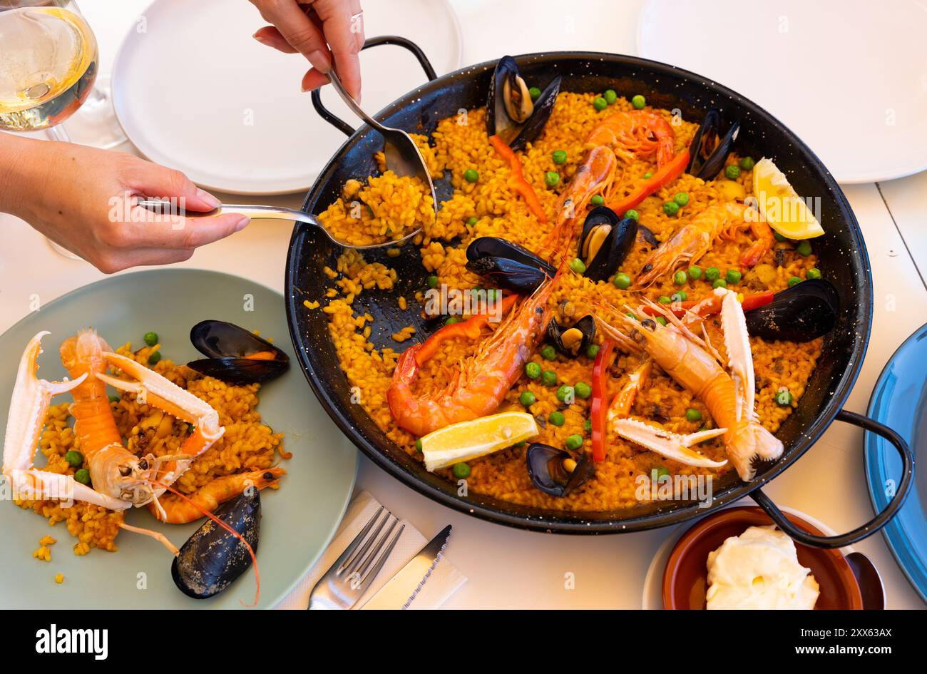 Paella with seafood - traditional Spanish dish. Female hands serving ...