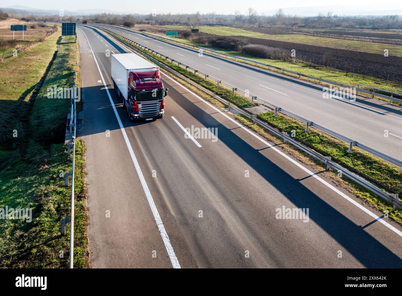 Large Red Transportation Truck with white trailer on a highway road ...