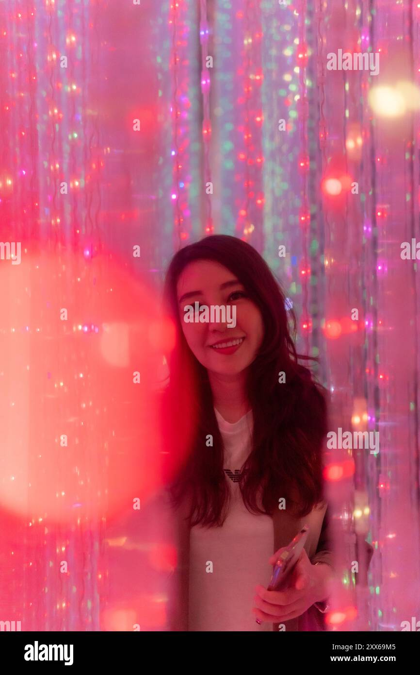 A woman poses surrounded by colorful LED lights in an immersive digital ...