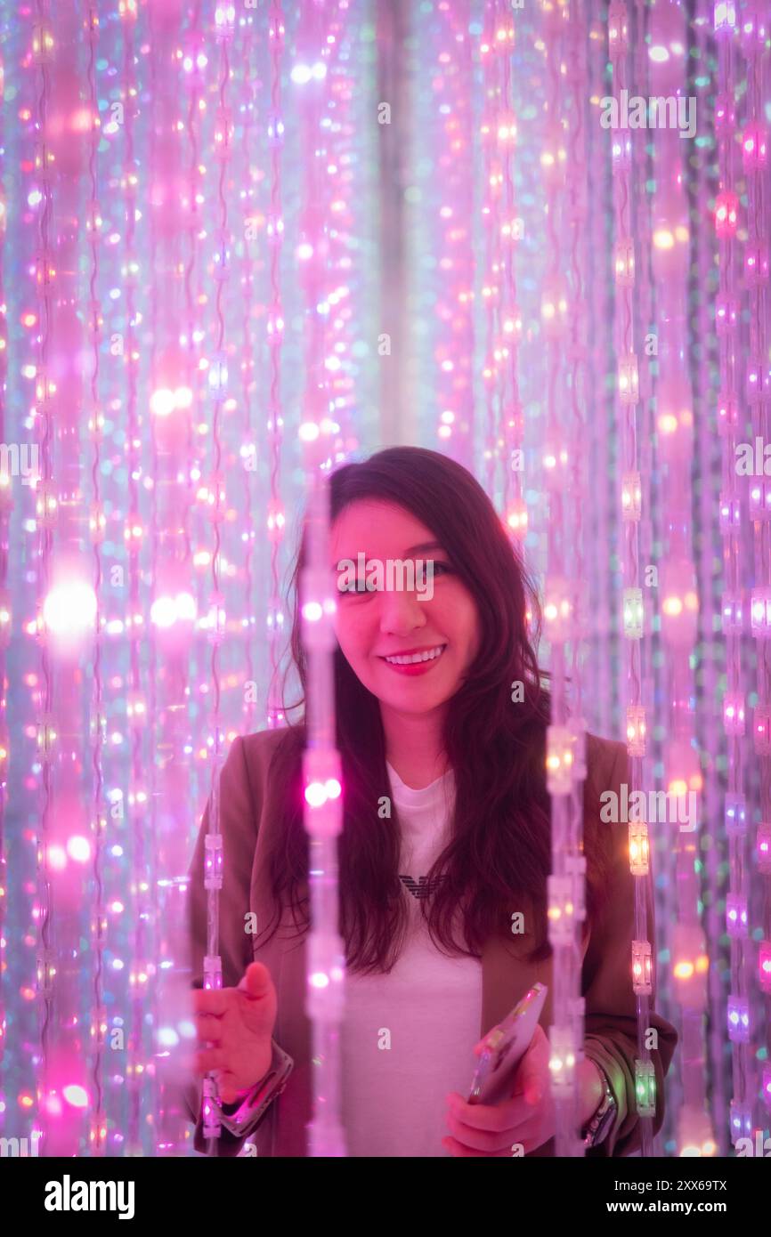 A woman poses surrounded by colorful LED lights in an immersive digital ...