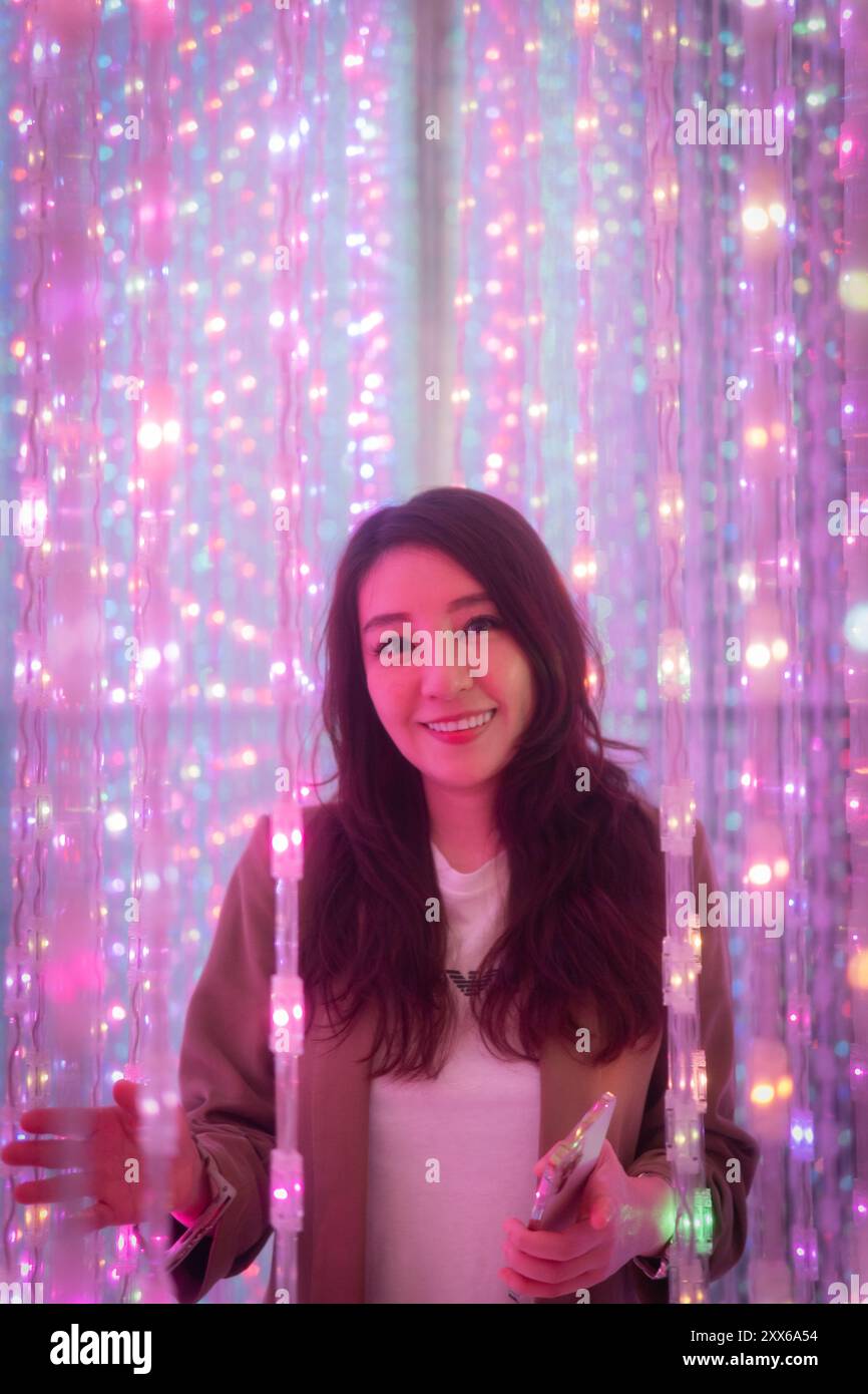 A woman poses surrounded by colorful LED lights in an immersive digital ...