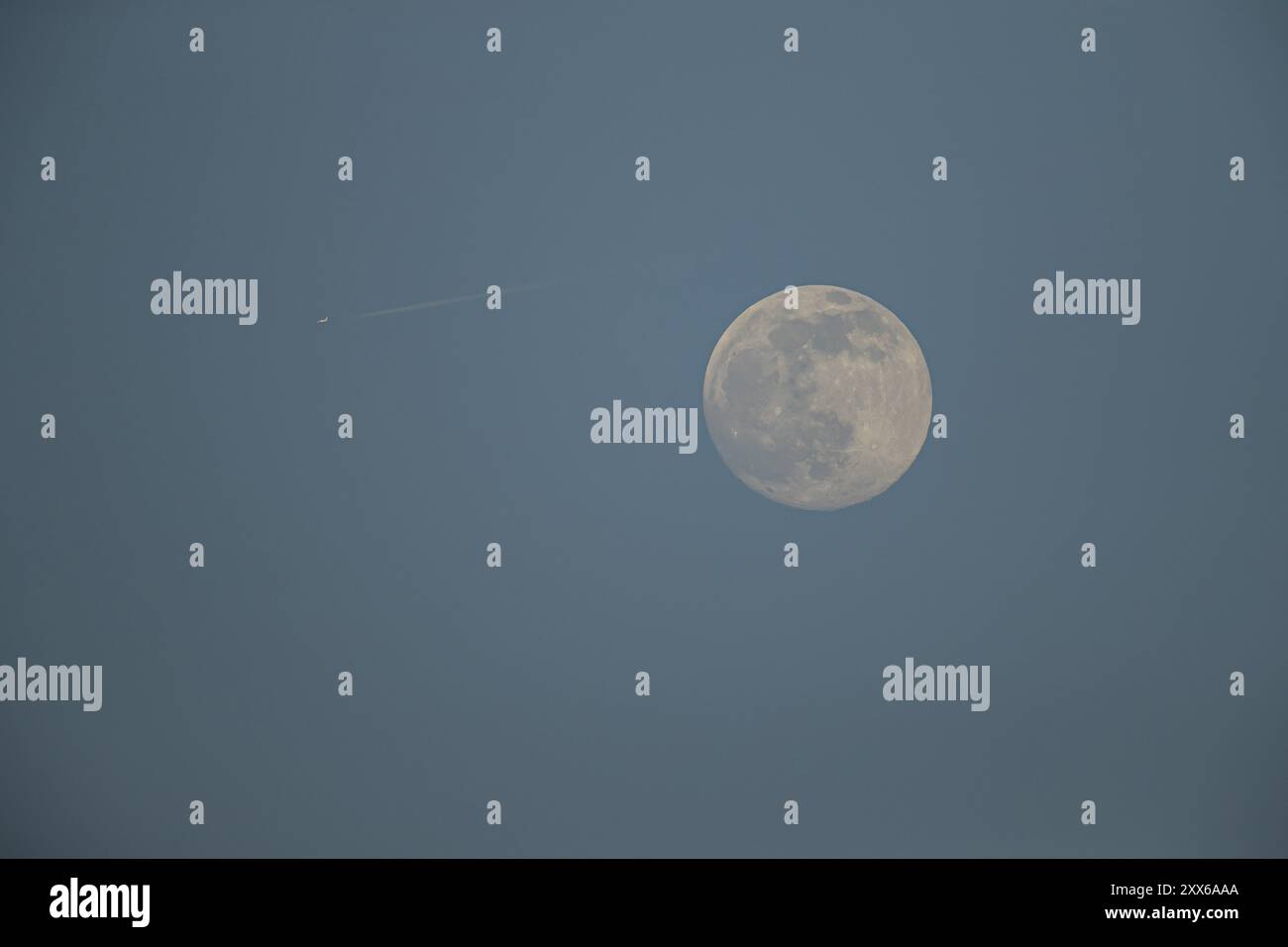 A full moon in the night sky with an aircraft flying passed it, England ...