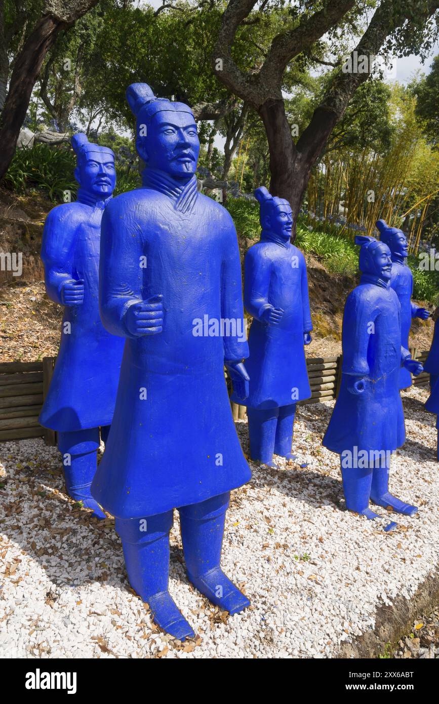 A group of blue terracotta warrior statues stands on gravel, surrounded ...