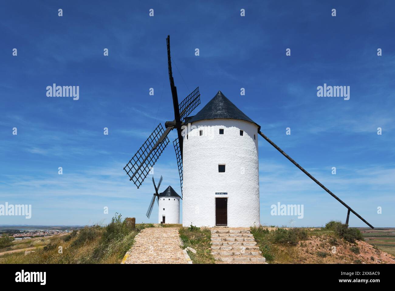 White windmill with blue conical roof on a hill under a clear blue sky ...