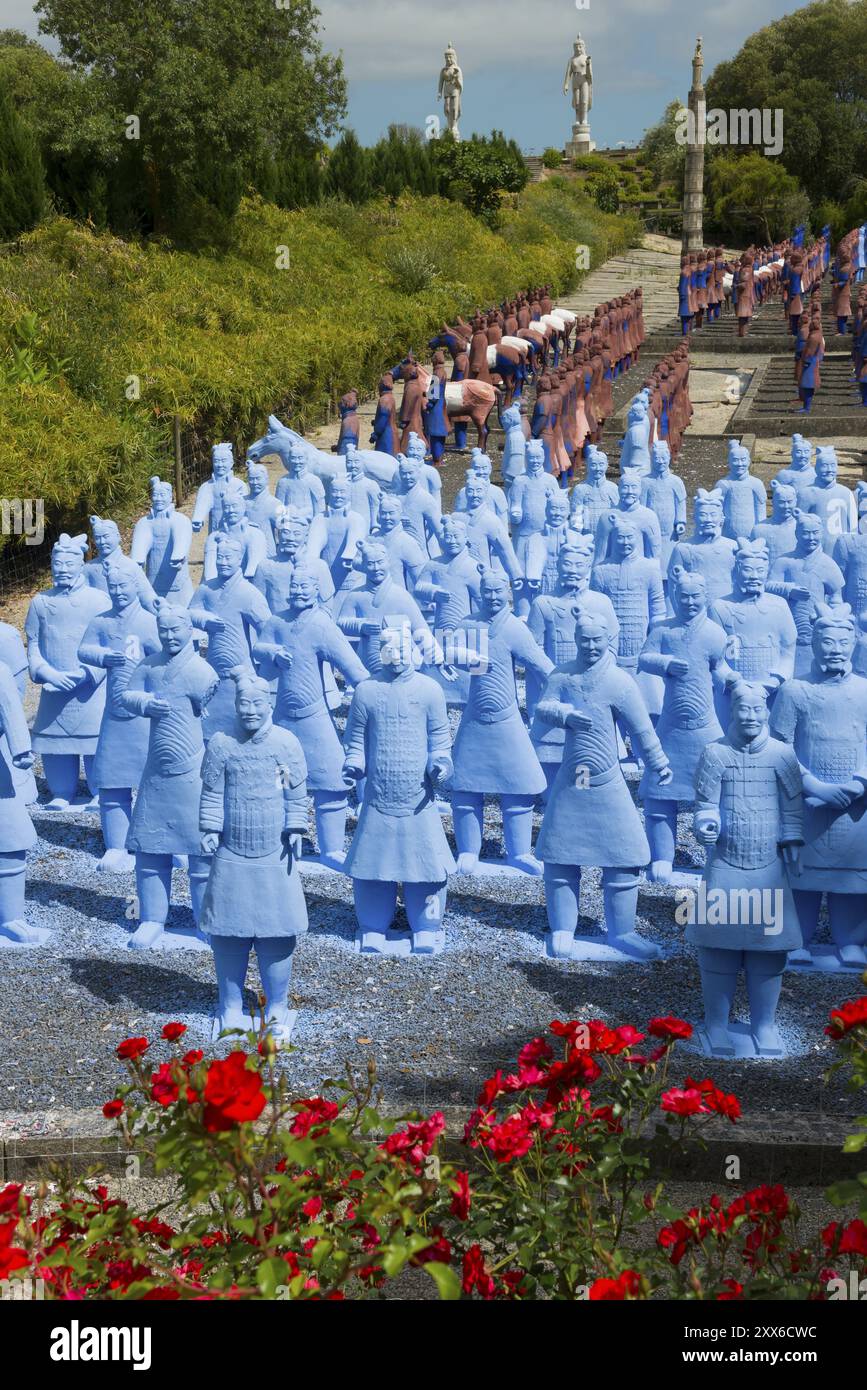A large number of blue terracotta soldier statues stand on a path lined ...