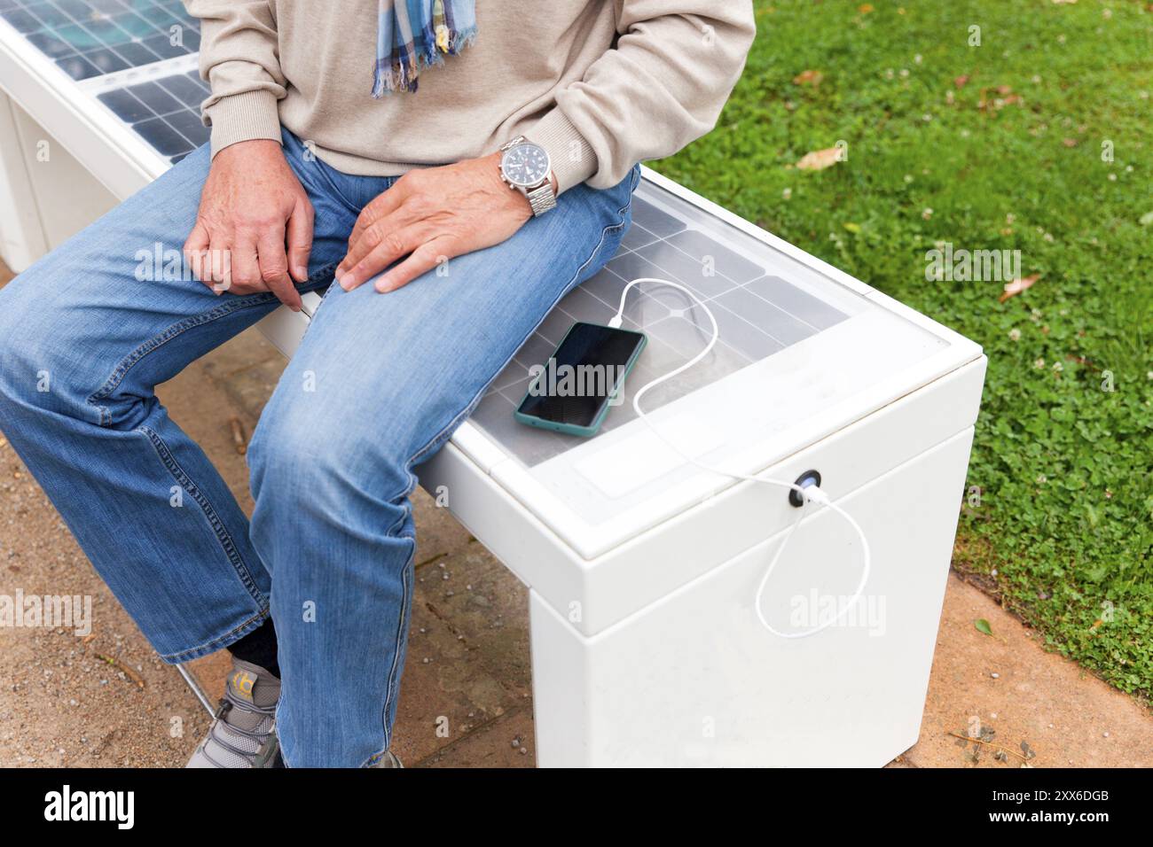 Man sits on a Smart Bench and charges his mobile phone, modern ...