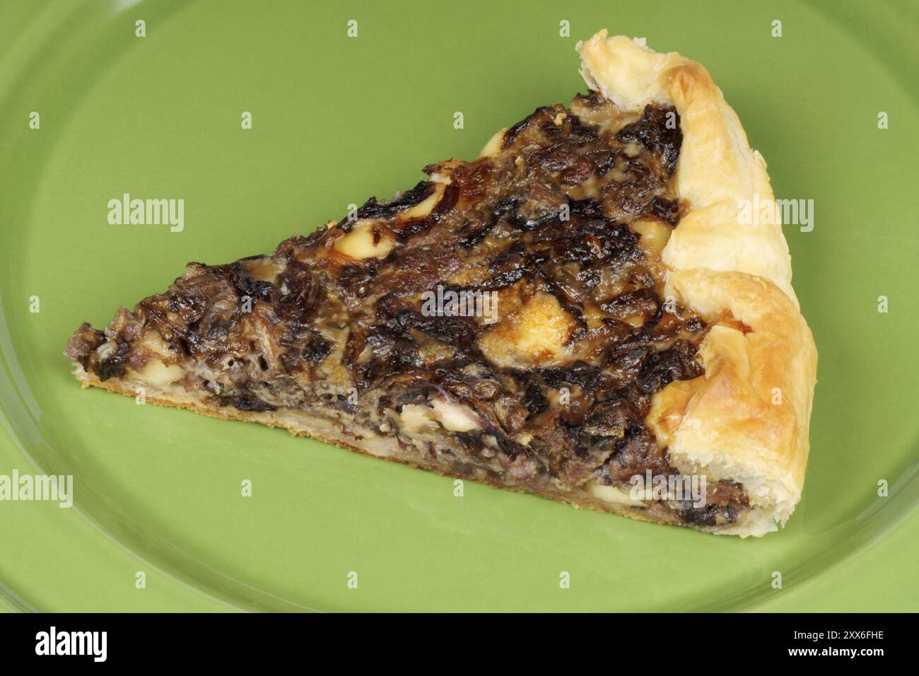 Slice of rustic french quiche with red chicory, bacon and cheese over a ...