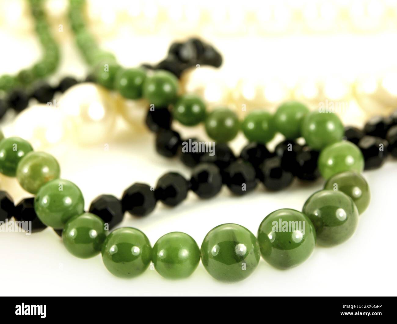 Green gemstone, white pearls, and black pearl necklace, isolated ...