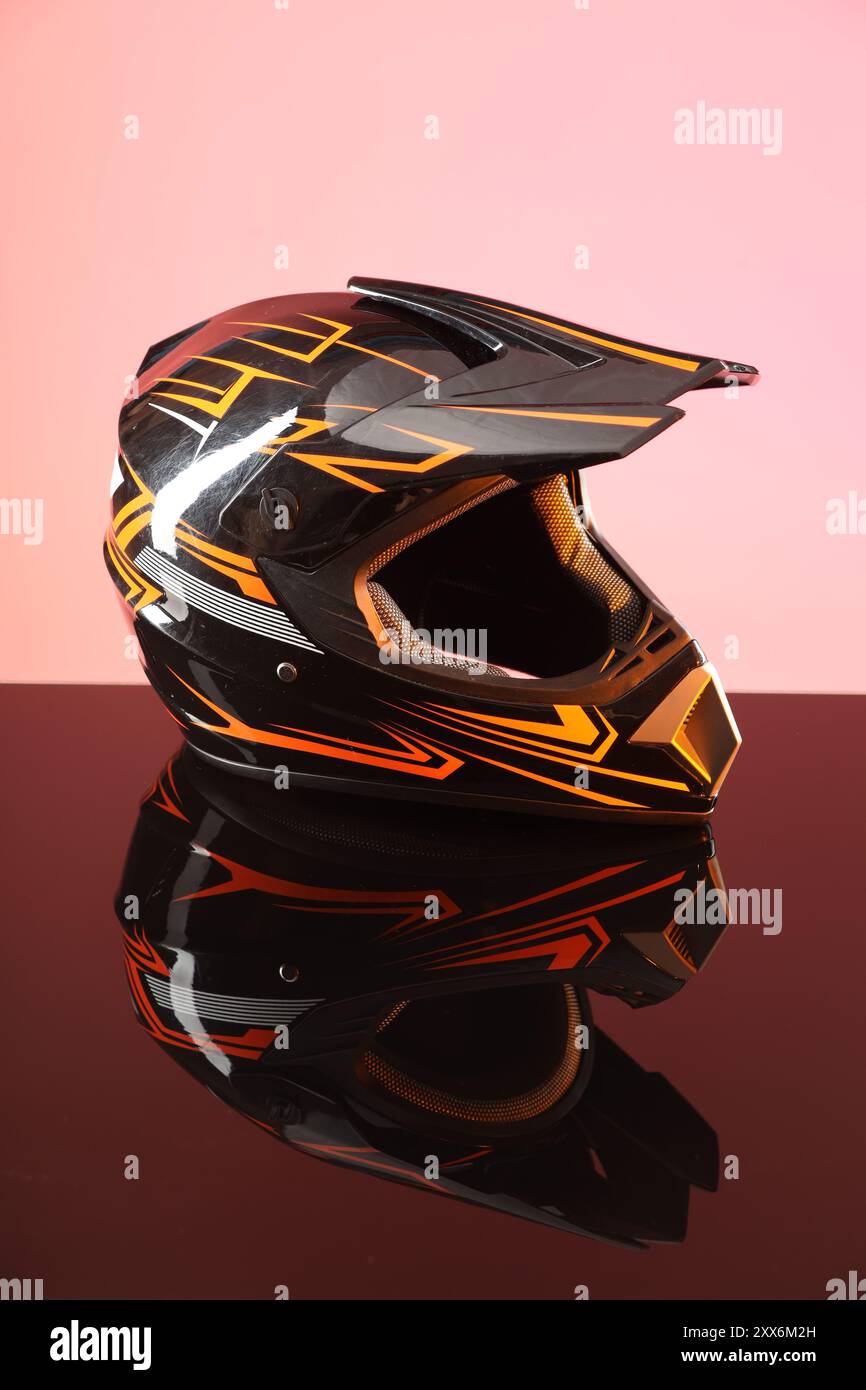 Modern motorcycle helmet with visor on mirror surface against pink ...