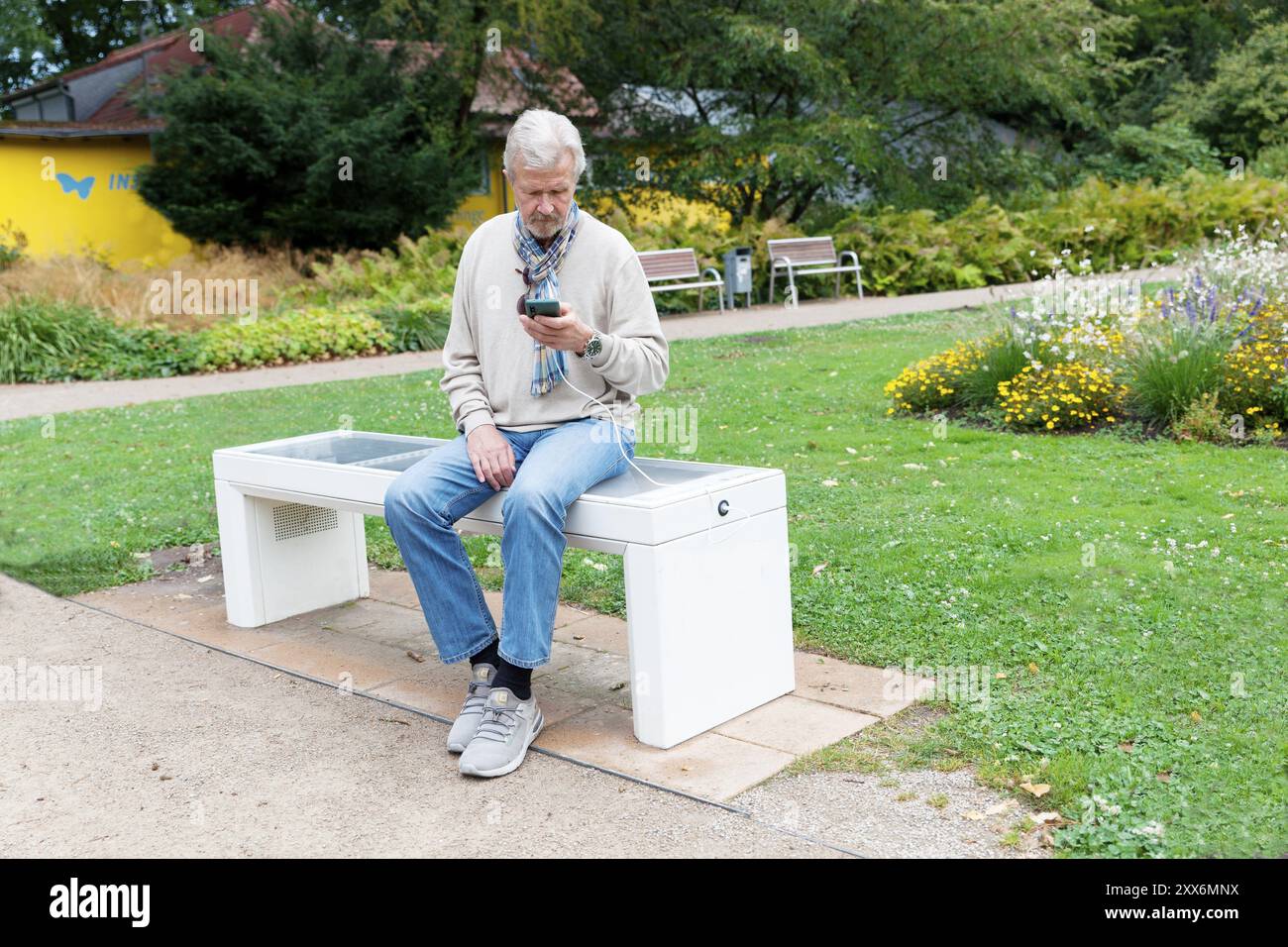 Man sits on a Smart Bench and charges his mobile phone, bench with ...