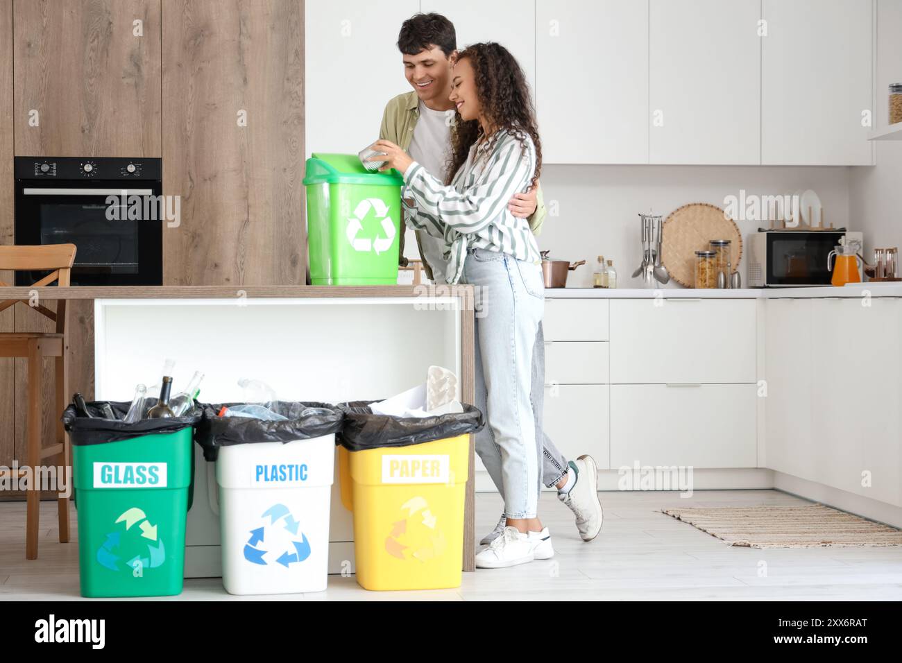 Young couple throwing can into garbage container in kitchen. Waste ...