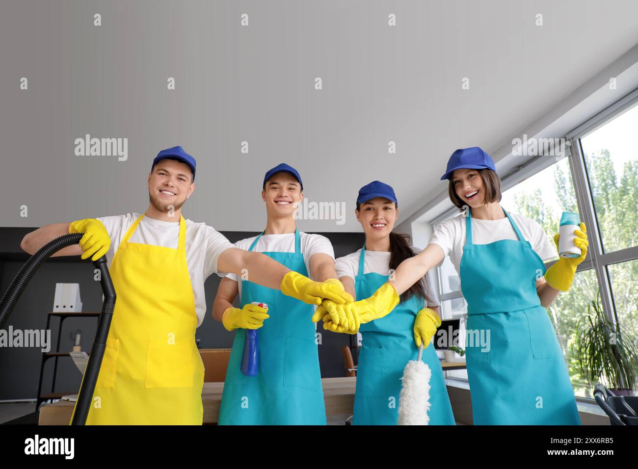 Group of young janitors putting hands together in office Stock Photo ...