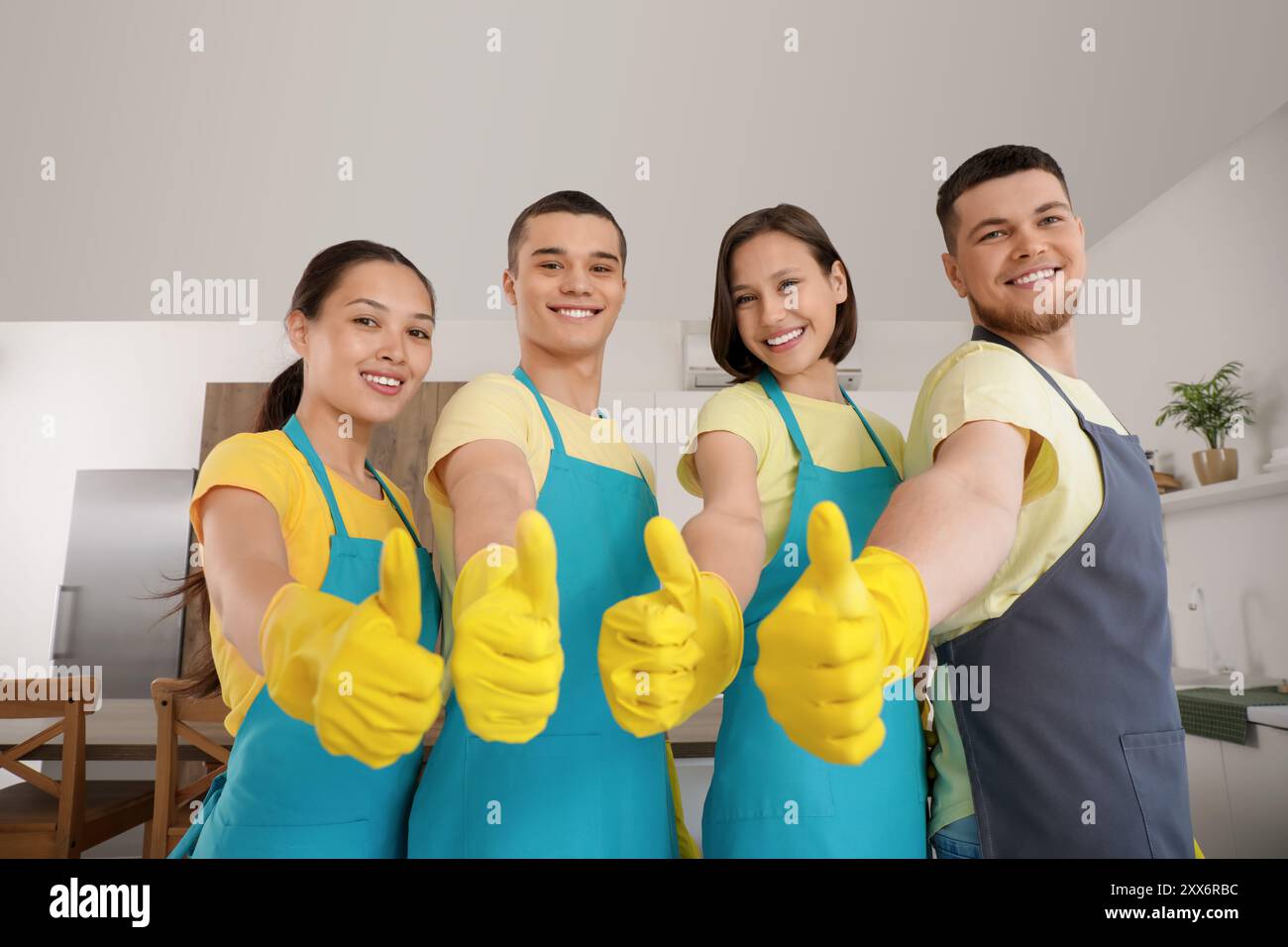 Group of young janitors showing thumbs-up in kitchen Stock Photo - Alamy