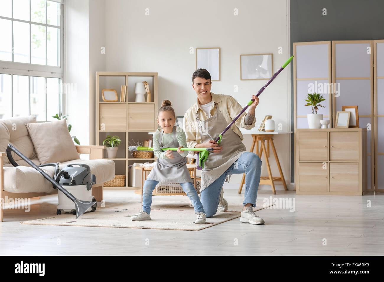Young father and his daughter having fun with floor mops at home Stock ...