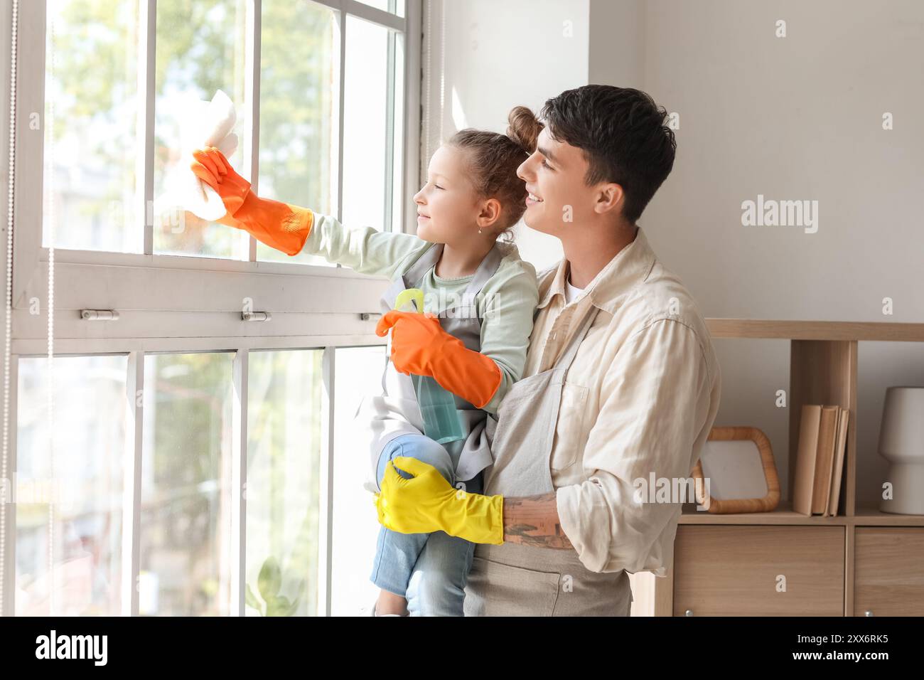 Young father and his daughter cleaning window together at home Stock ...