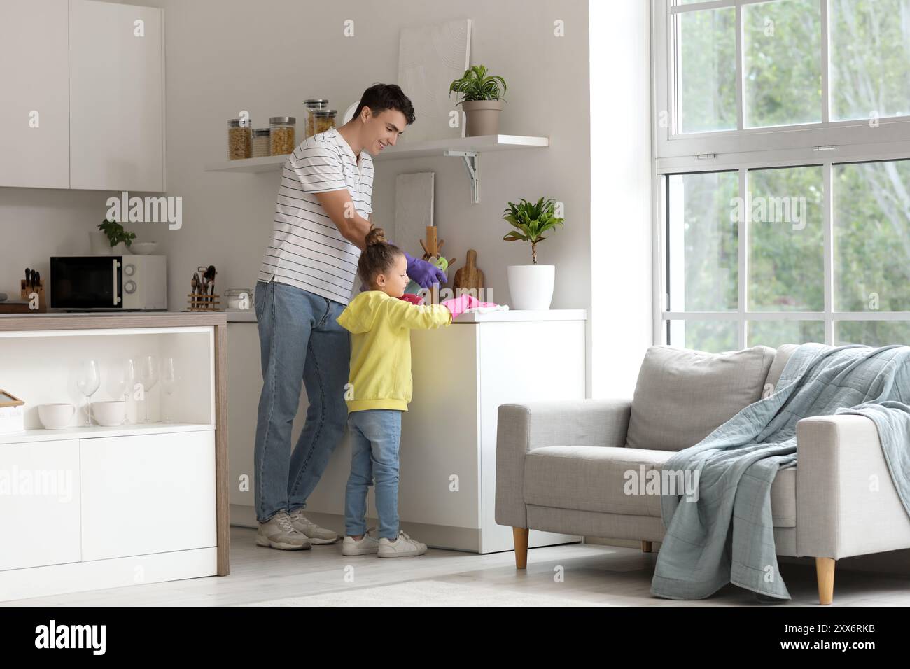 Young father and his daughter cleaning counter together in kitchen ...