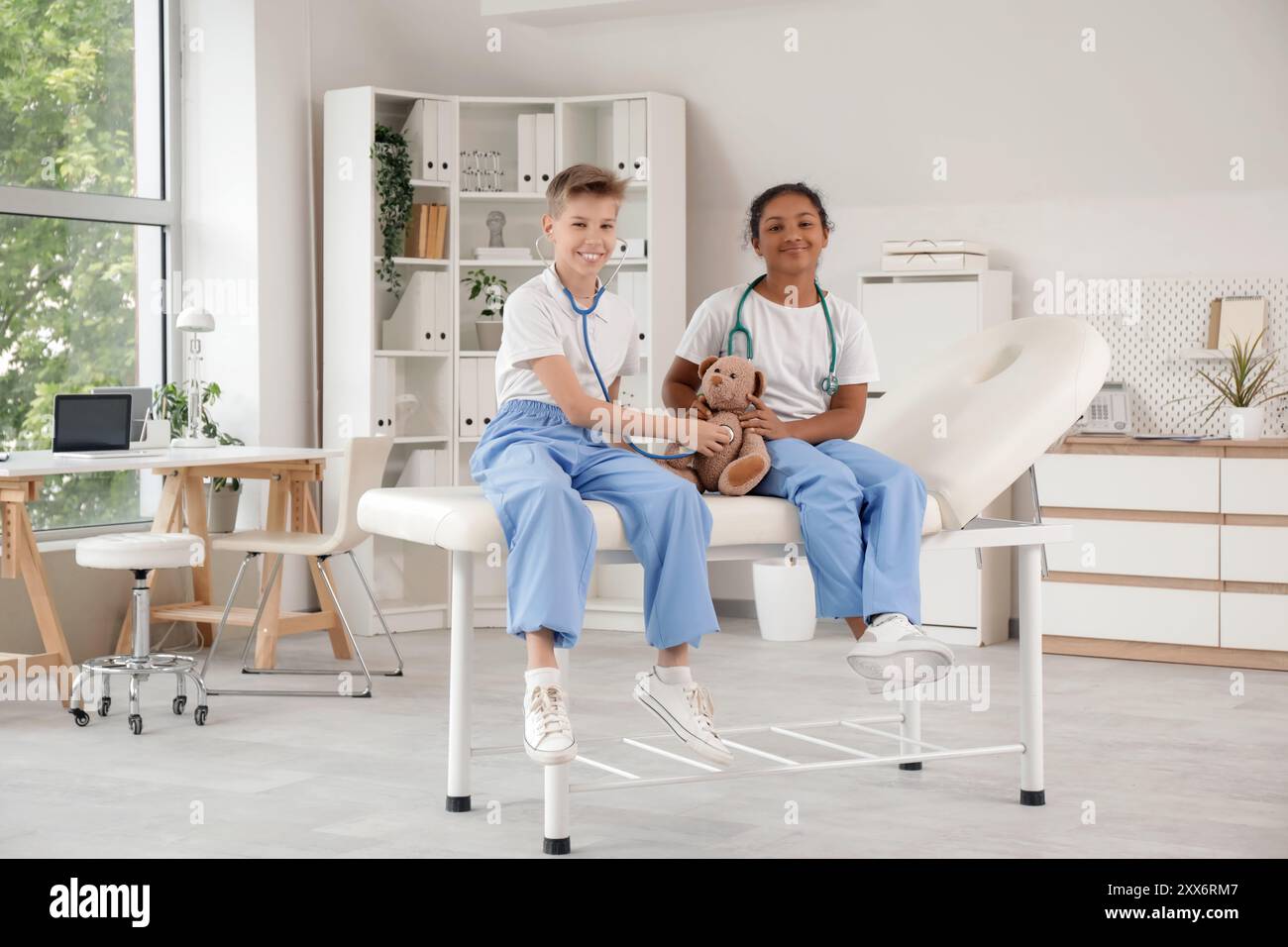 Teenage doctors examining teddy bear with stethoscope in clinic Stock ...