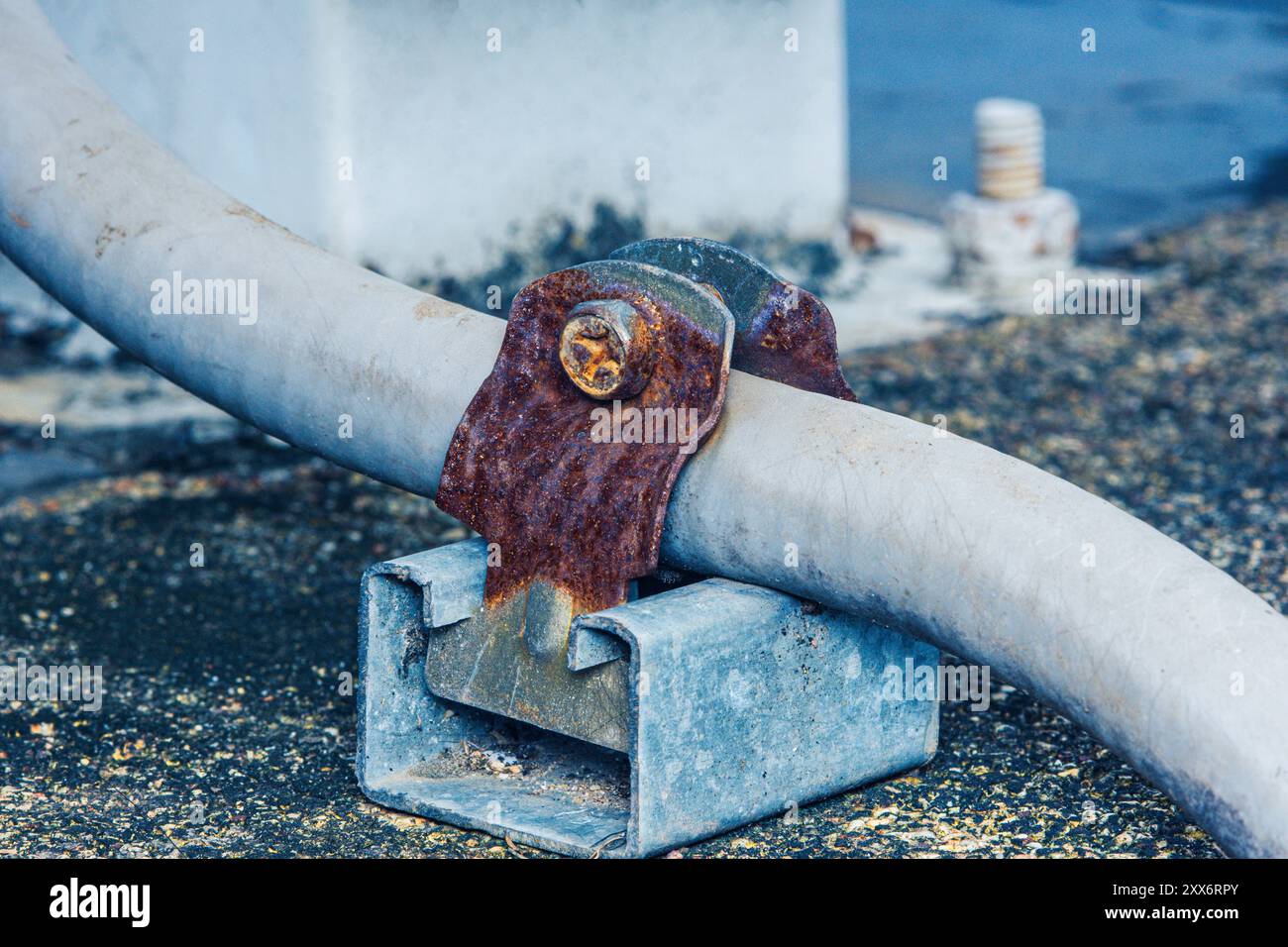 Rusty metal clamp holding electrical conduit on rooftop Stock Photo - Alamy