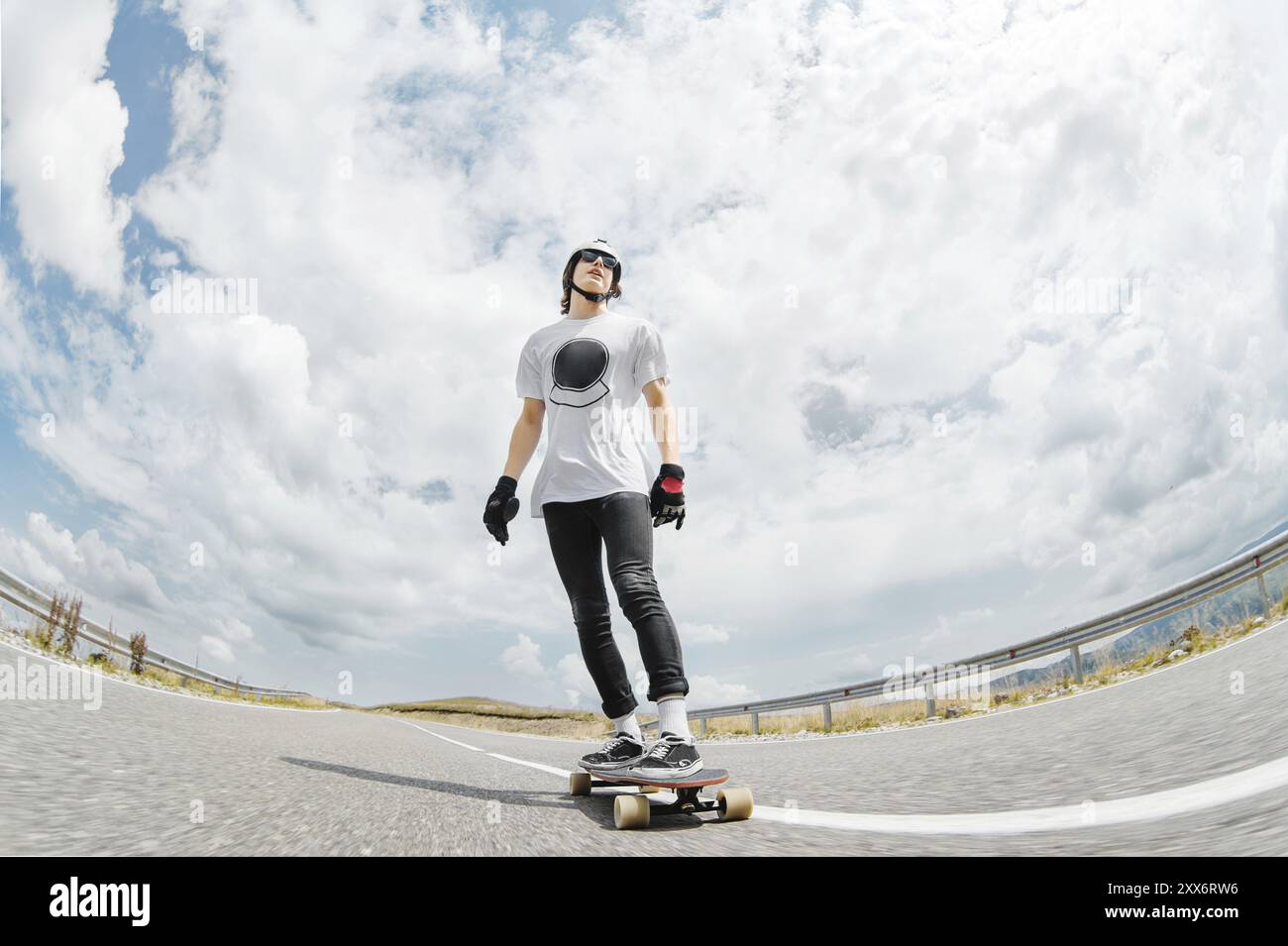 The guy in the helmet and sunglasses very quickly rides his longboard ...