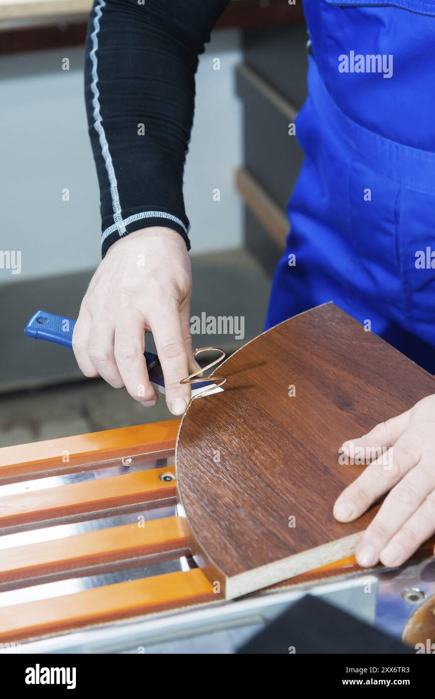 A professional carpenter processes the plastic edges of the countertop ...