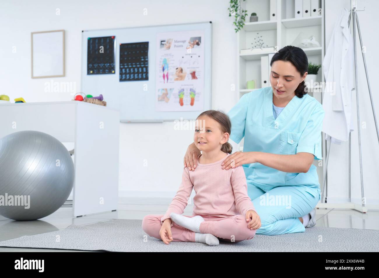 Female osteopath with little patient stretching and doing exercises in ...