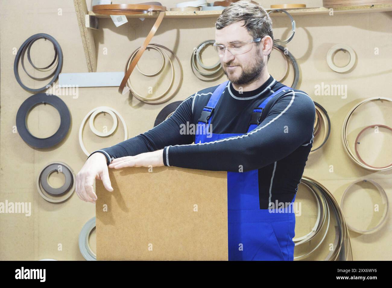 The manufacturer of furniture in special clothes and goggles keeps an ...