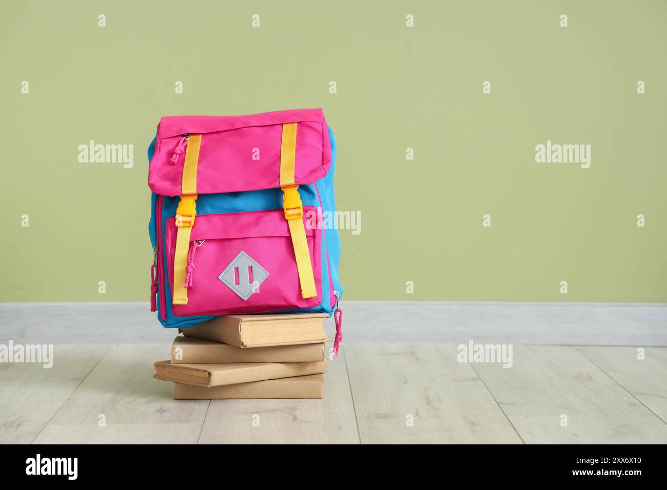 School bag with books on floor against green background Stock Photo - Alamy