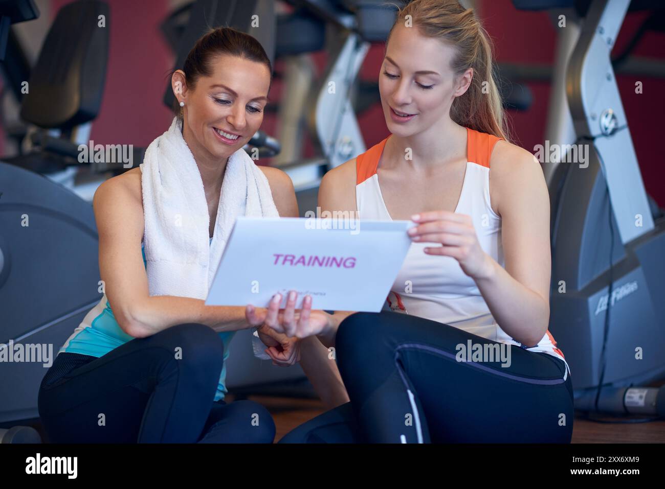 Attractive fit young female athlete with her personal trainer holding ...