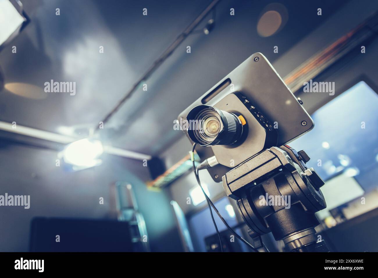 Film camera on a tripod in a television broadcasting studio, spotlights ...