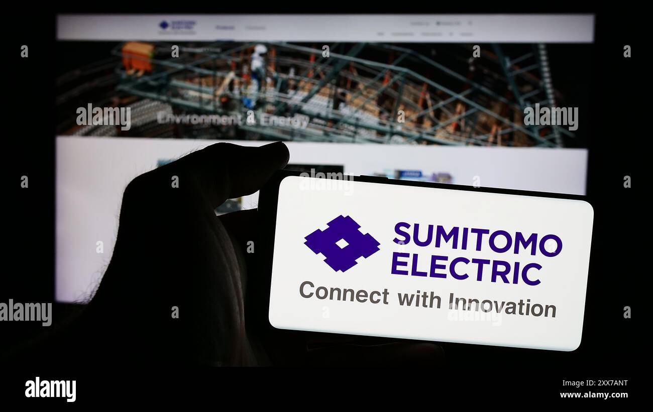 Person holding mobile phone with logo of Japanese company Sumitomo ...
