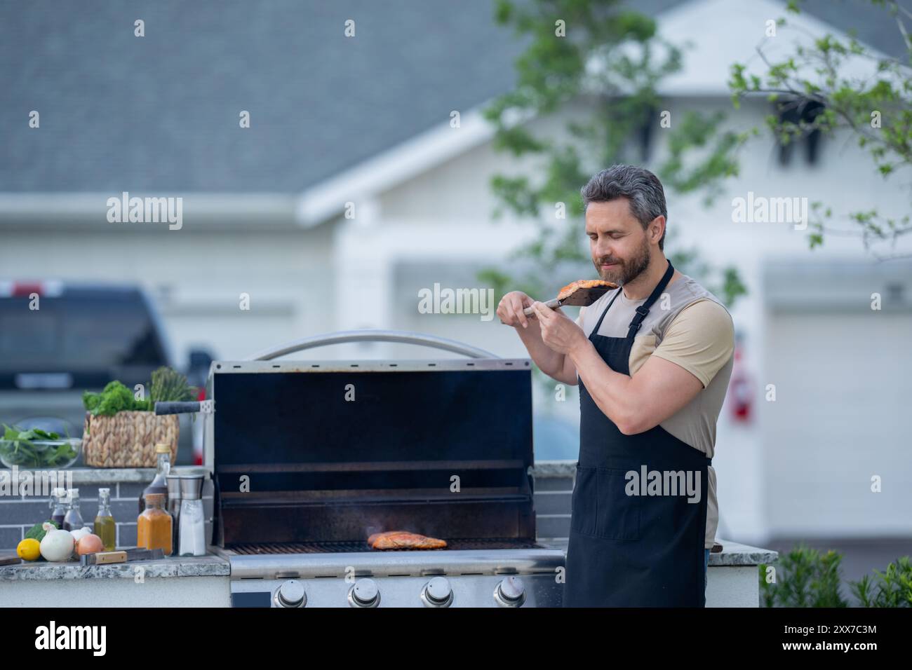 Handsome smiling hispanic man making barbecue at backyard. Picnic ...