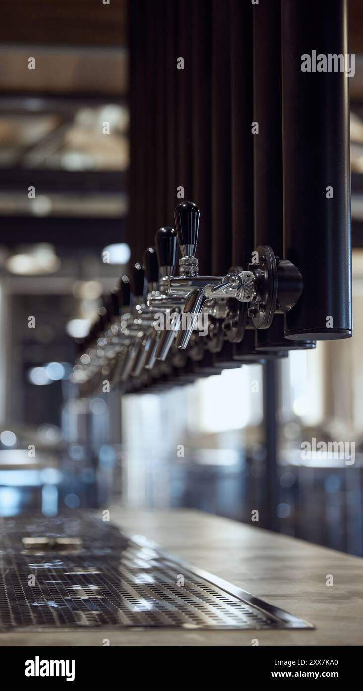 Row of shiny chrome beer taps with black handles, hanging from long ...
