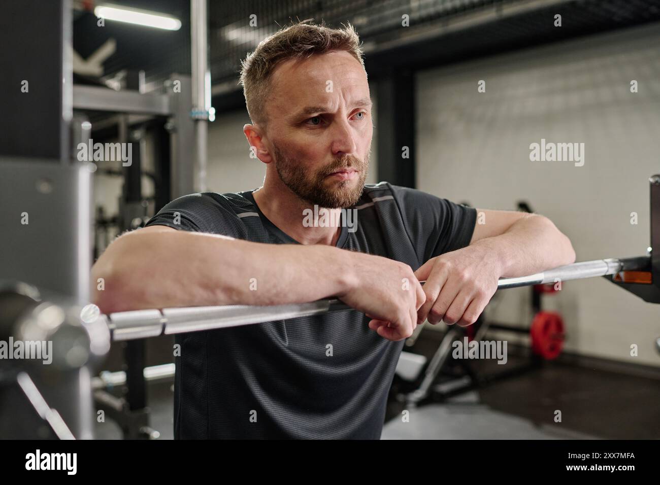 Bodybuilder leaning on metal barbell while resting after set Stock ...