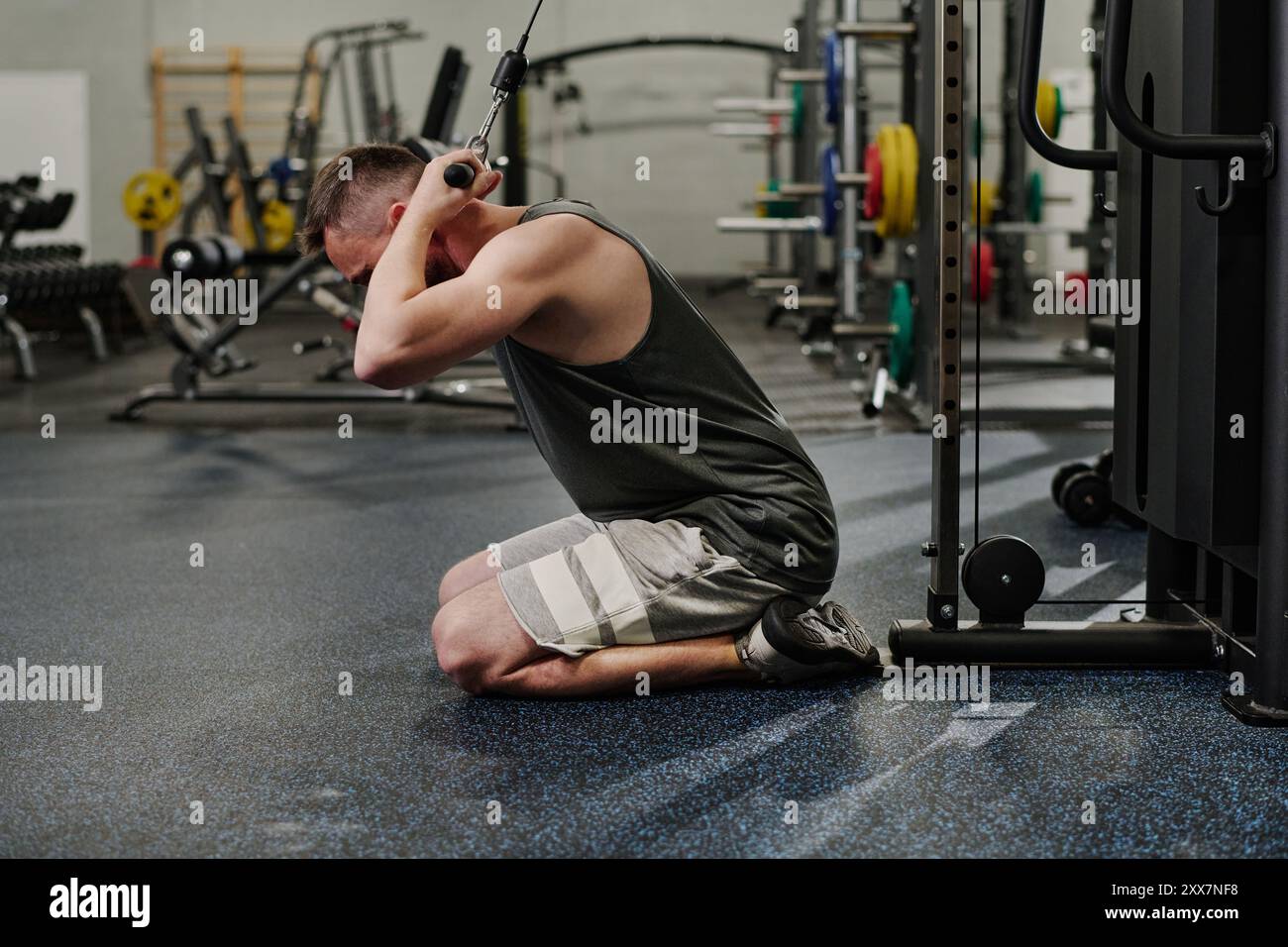 Shredded man using weight machine while sitting on floor and doing ...