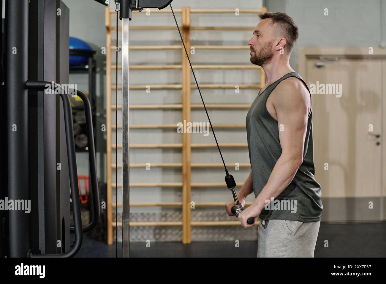 Ripped man using weight lifting machine to develop biceps and triceps ...